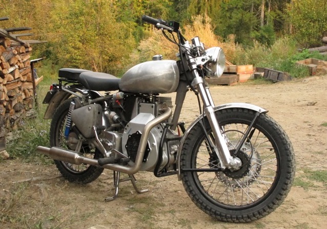 Foto de uma moto Sommer Diesel prateada, estacionada na terra.