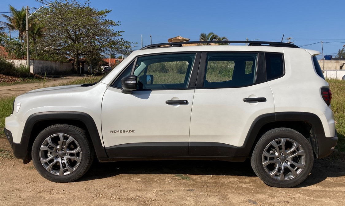Foto de um Jeep Renegade 2022 branco estacionado de lado. Na paisagem o chão é de terra, há um ...