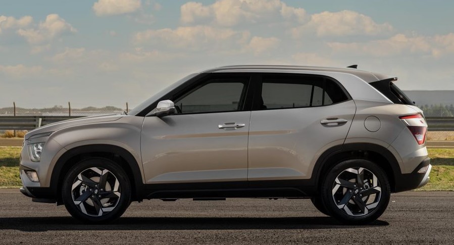 Foto da lateral esquerda do Creta G2. O carro é prateado, tem teto ...