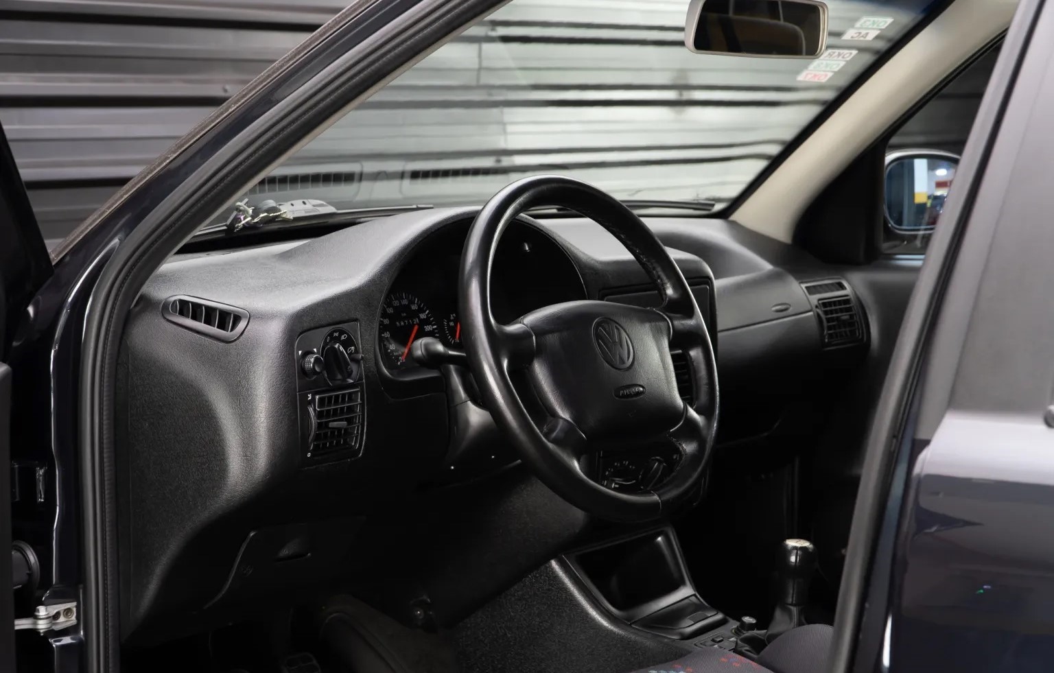 Foto mostrando o volante e o painel do carro, que são em plástico ...