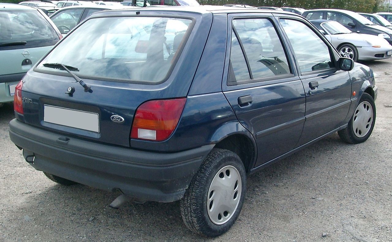 Foto mostrando atraseira de um Ford Fiesta 1995 azul estacionado.