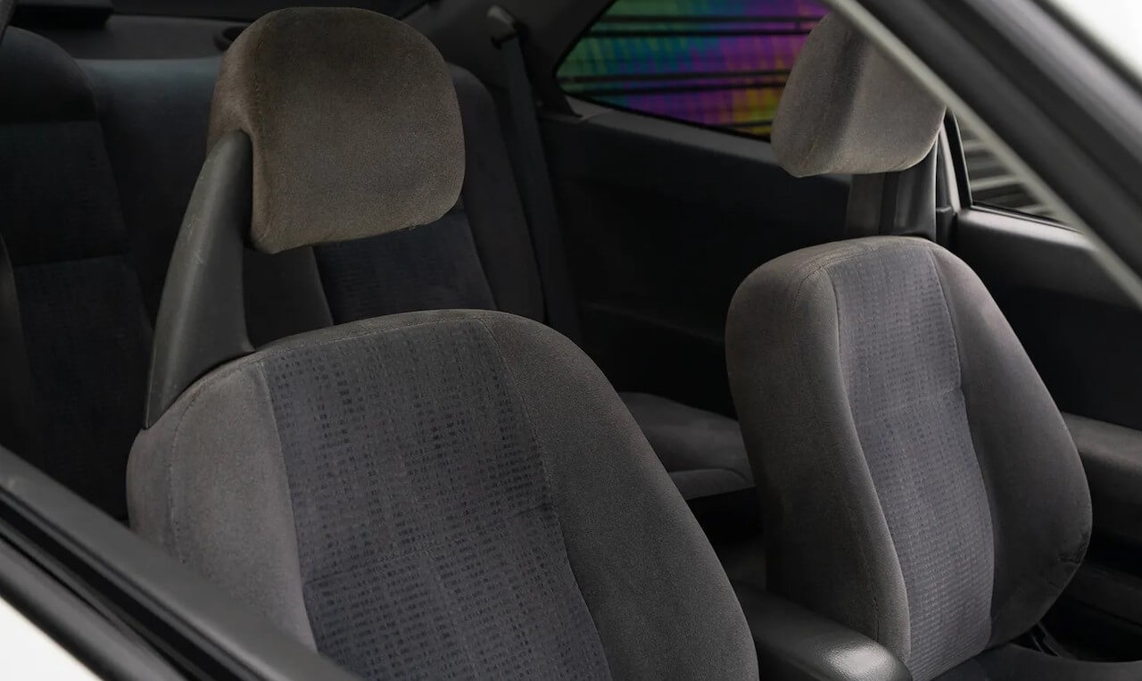 Foto mostrando os bancos dianteiros do carro, que são em tecido cinza ...