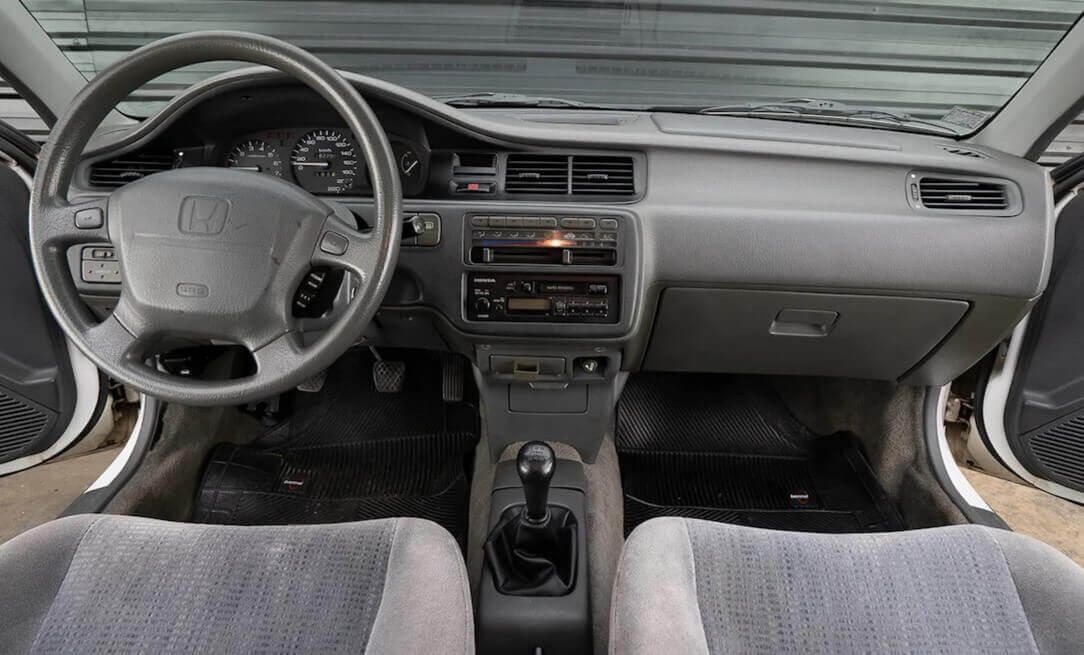 Foto mostrando a cabine do carro. É possível ver o volante, o painel, o ...