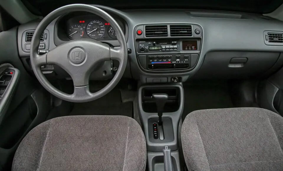 Foto mostrando a cabine do carro. É possível ver o volante, o painel, o ...