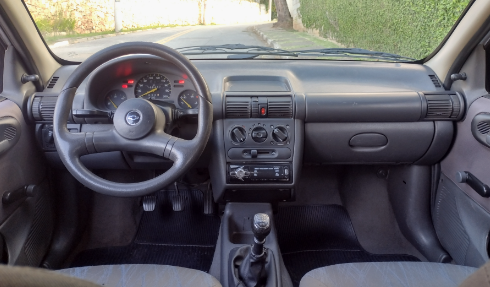 Foto mostrando a cabine do carro. É possível ver o volante, o painel, o ...
