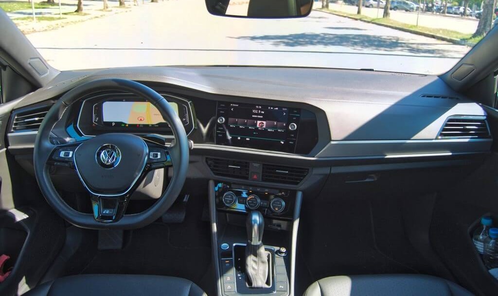 Foto mostrando a cabine do carro. É possível ver o painel, o volante, o ...