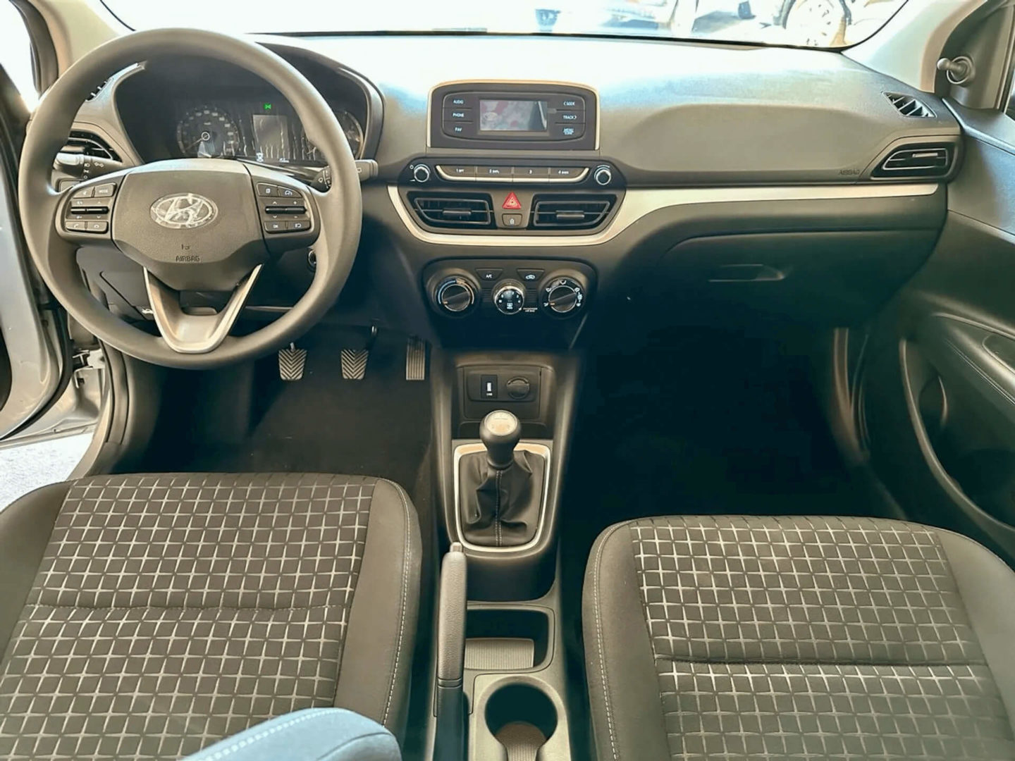 Foto interior do Hyundai HB20 Sense Plus 2024, exibindo o painel, central multimídia e parte dos ...