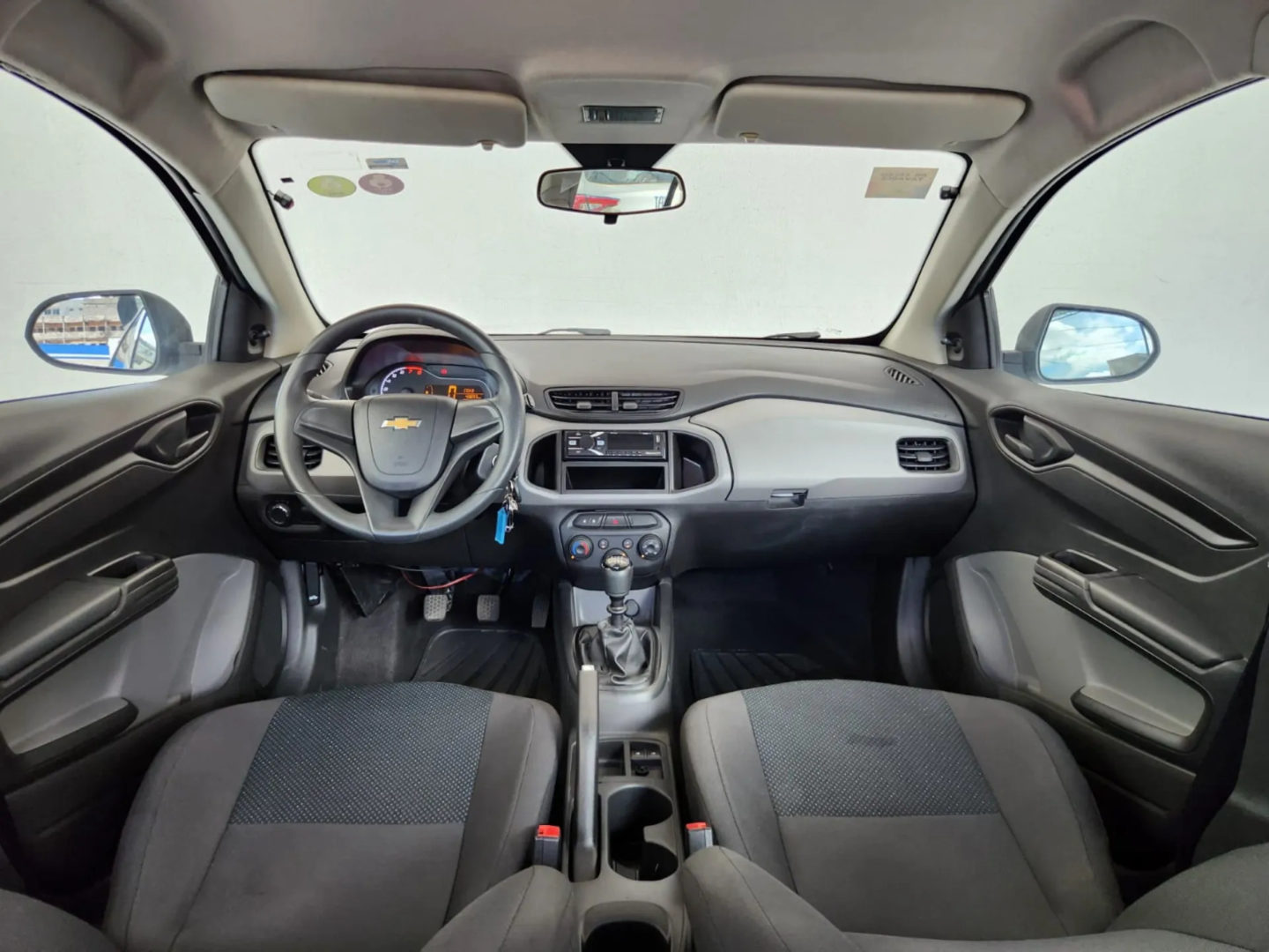 Foto interna do Chevrolet Onix Joy, exibindo o volante, painel de ...