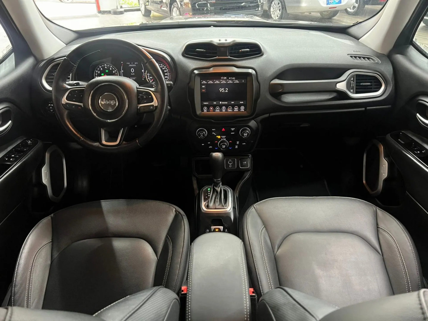 Foto interna do carro, exibindo o volante, painel de instrumentos, central multimídia, parte dos ...