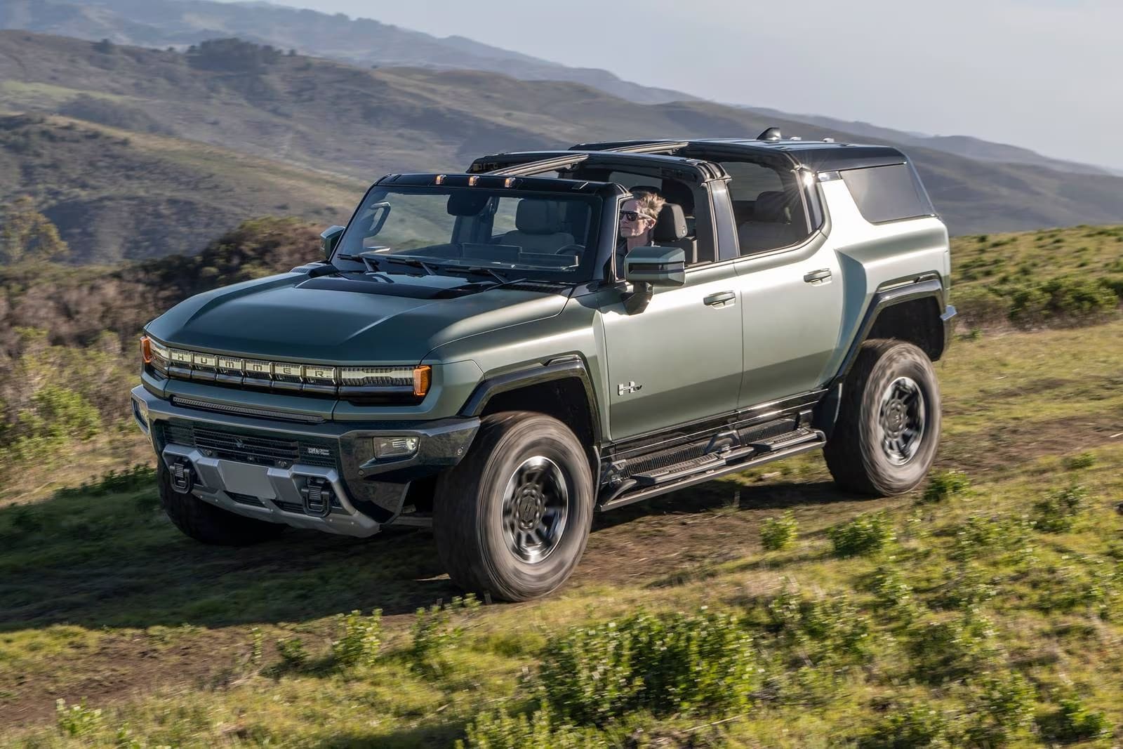 Foto diagonal do Hummer EV SUV 2024, sem o teto descendo uma estrada de ...